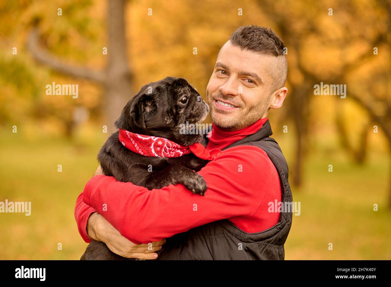 A man standing in the park and hugging his dog Stock Photo - Alamy