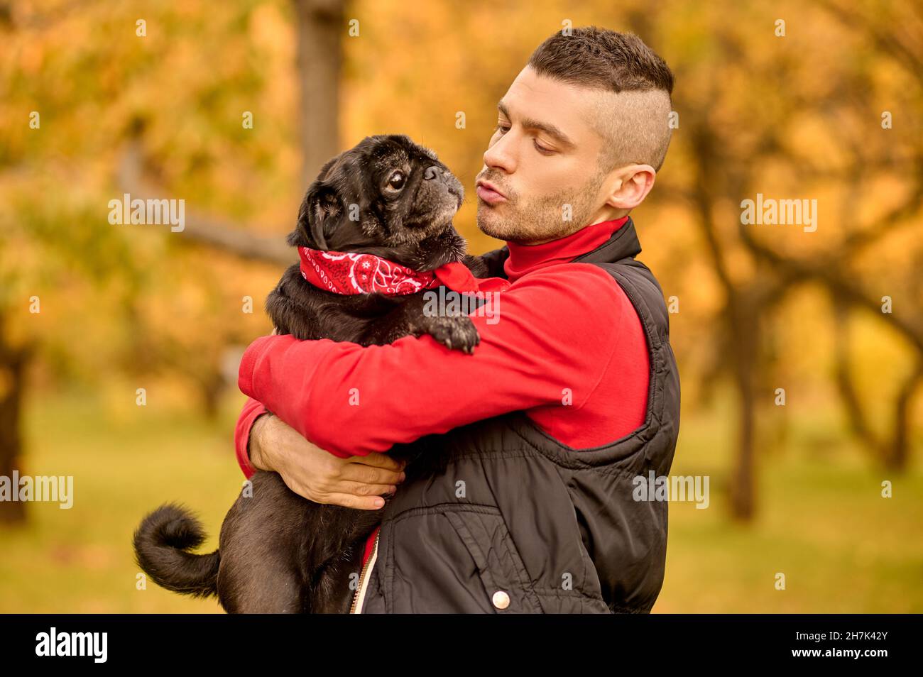 A man standing in the park and hugging his dog Stock Photo - Alamy