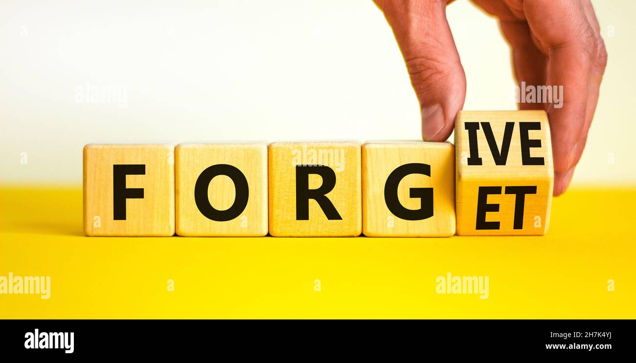Forgive and forget symbol. Businessman turns a wooden cube and changes ...