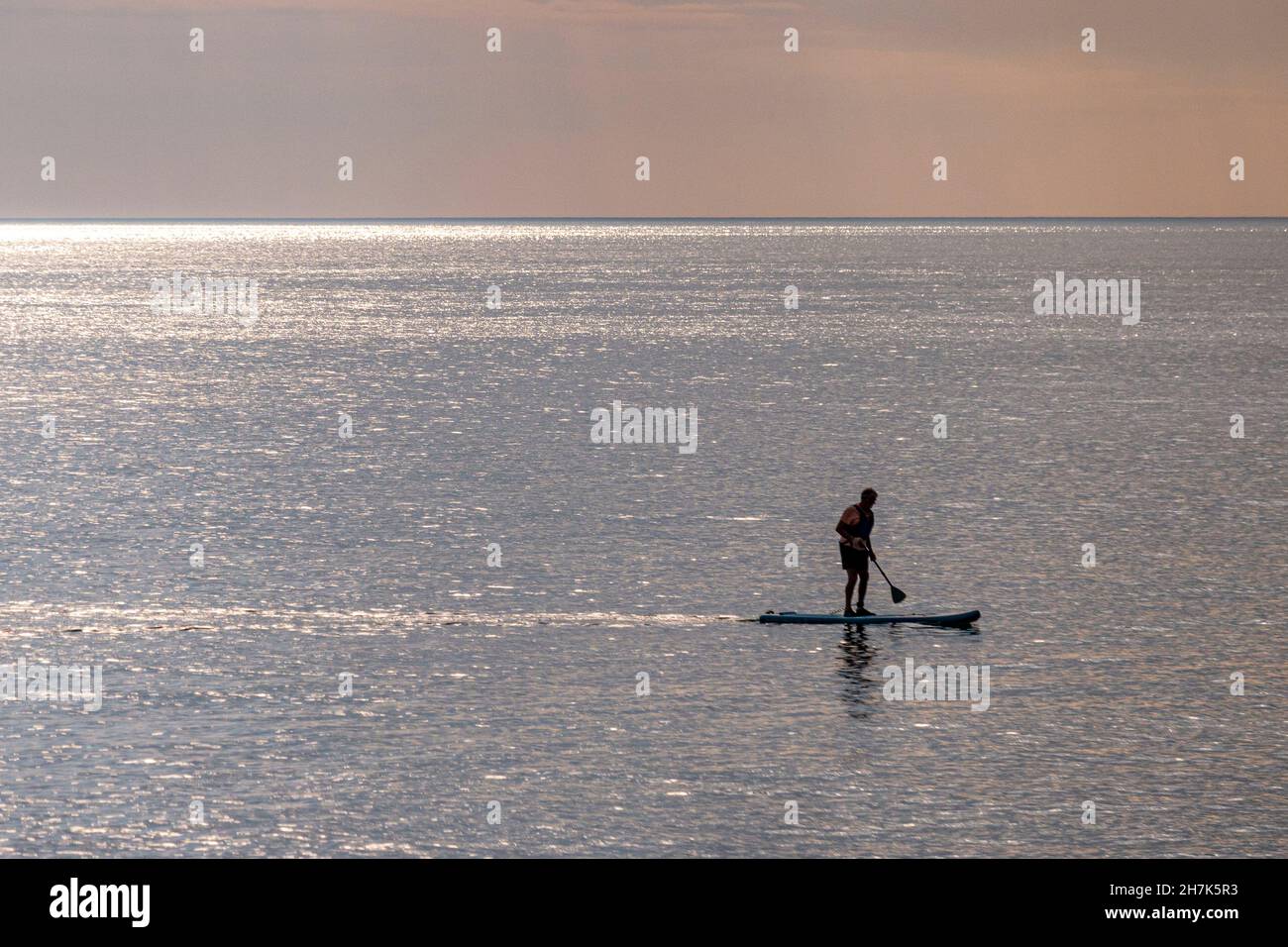 Paddleboarder on a calm sea off Ferring, West Sussex, UK Stock Photo ...