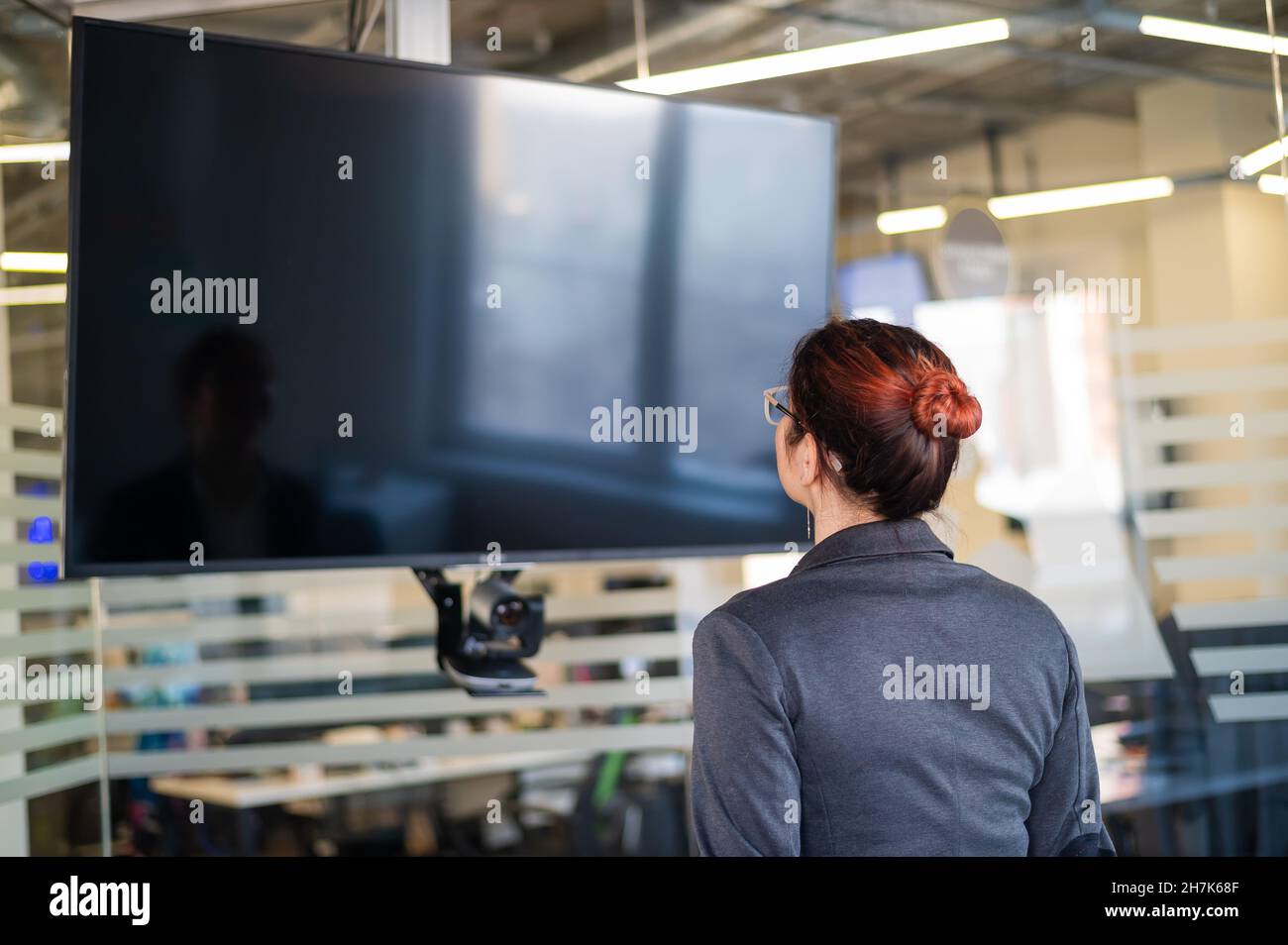 Business woman looking at the TV screen in the office Stock Photo - Alamy