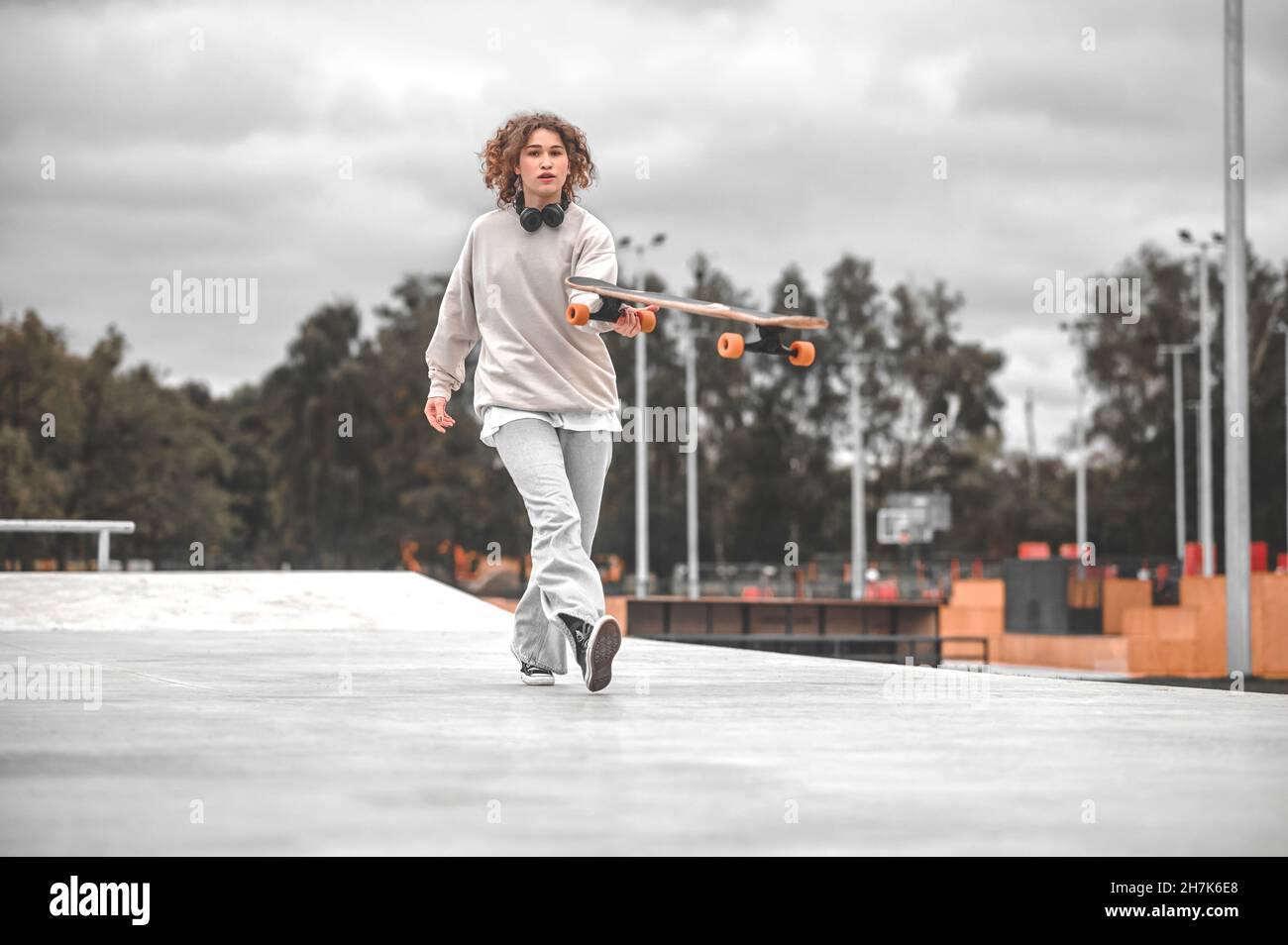 Girl walking in park with skeetboard Stock Photo - Alamy