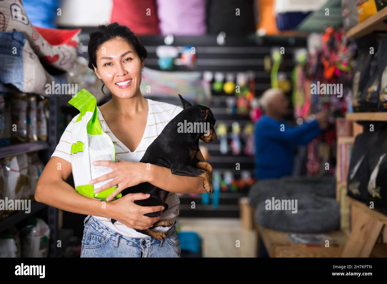 Happy female customer with dog choosing dry food in pet shop Stock ...