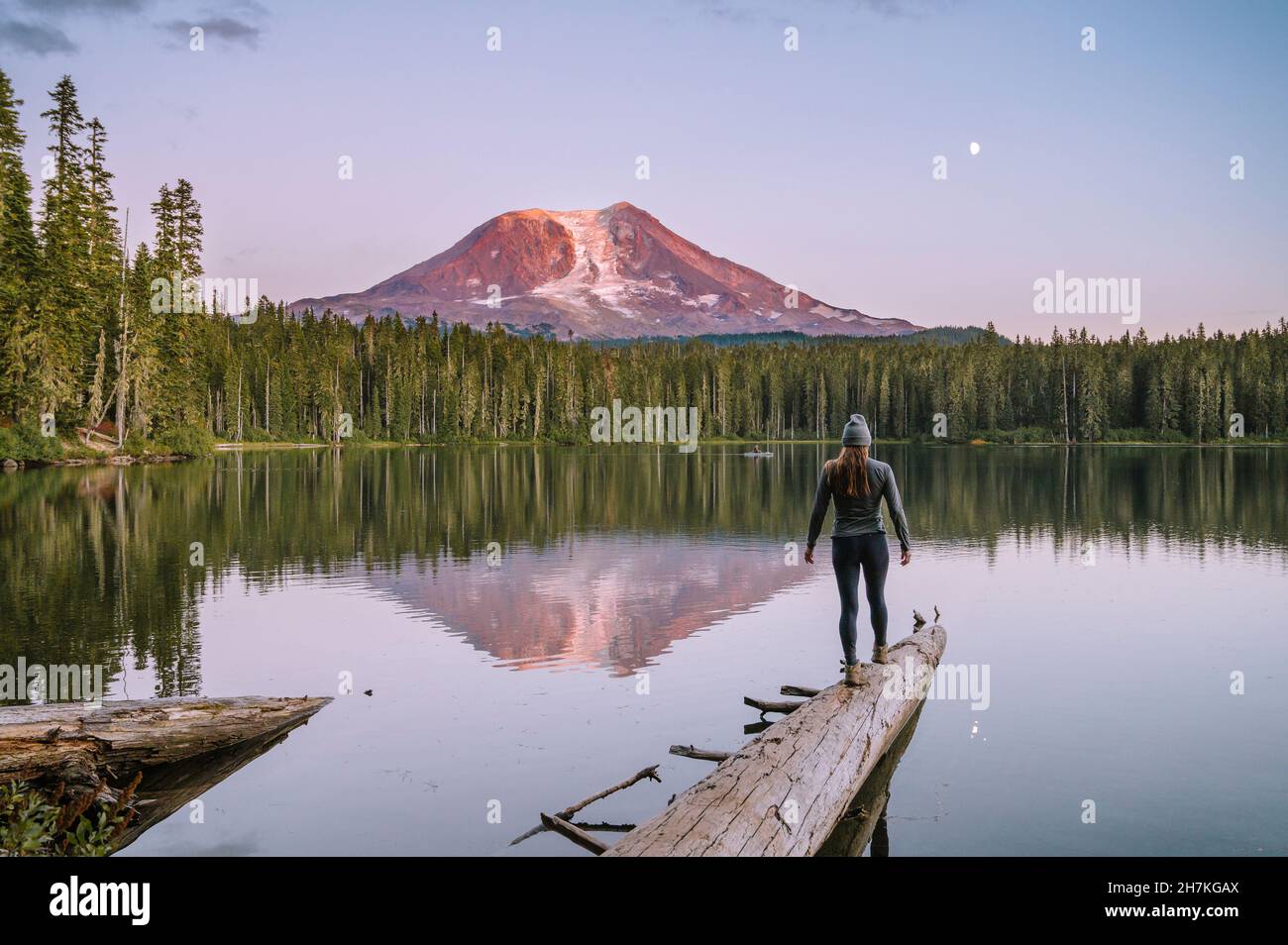 Female balancing on a log with Mount Adams reflecting in the lake Stock ...