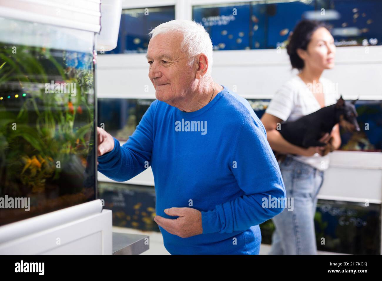 Positive mature man chooses aquarium fish in pet shop Stock Photo - Alamy
