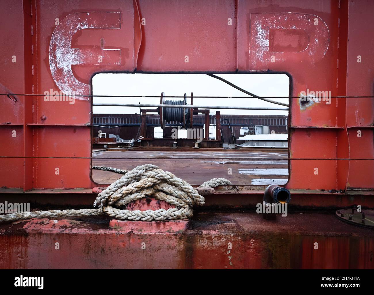 Mooring rope tied to a metal piling with a metal window opening at the ...