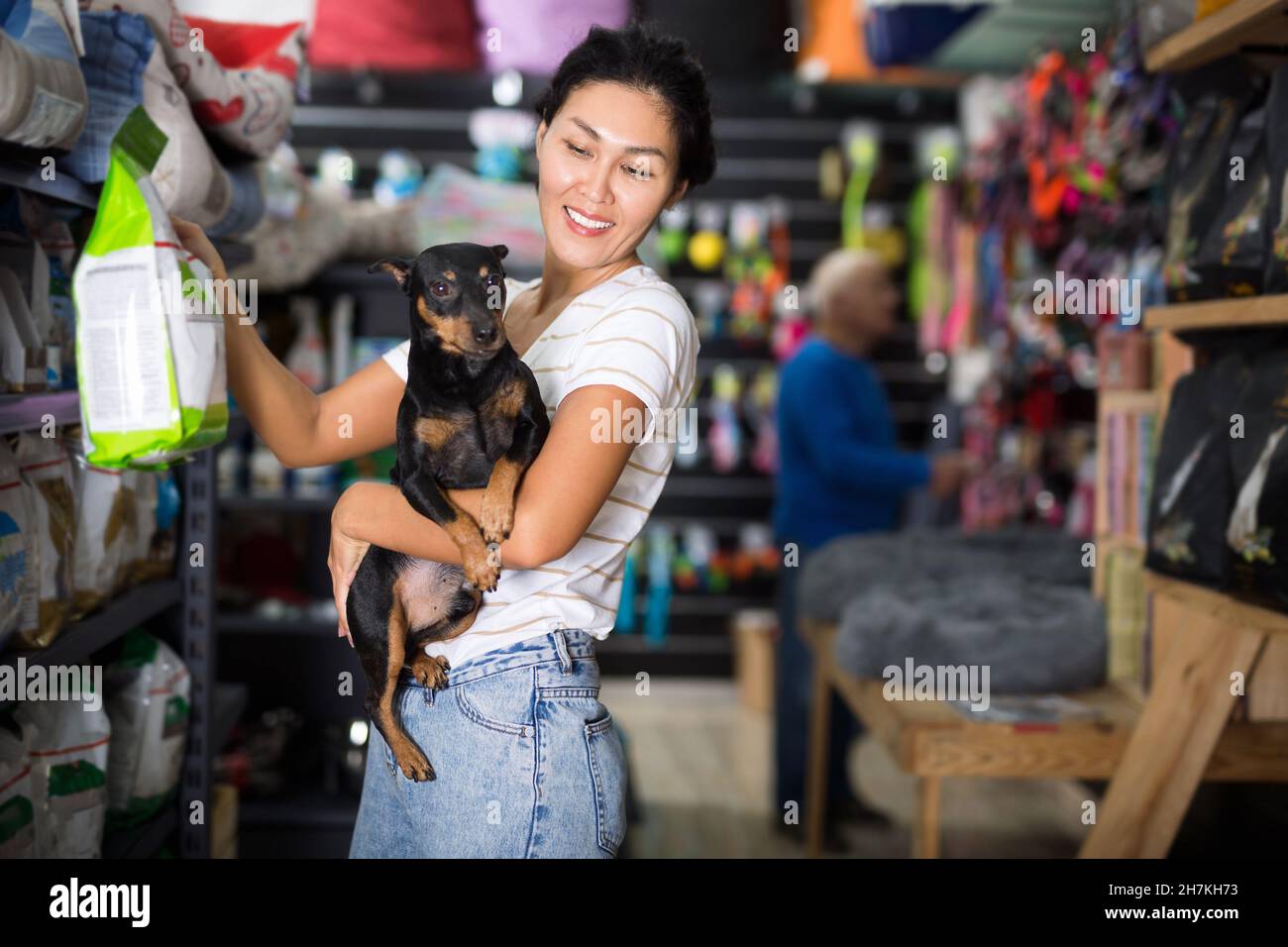 Happy female customer with dog choosing dry food in pet shop Stock ...