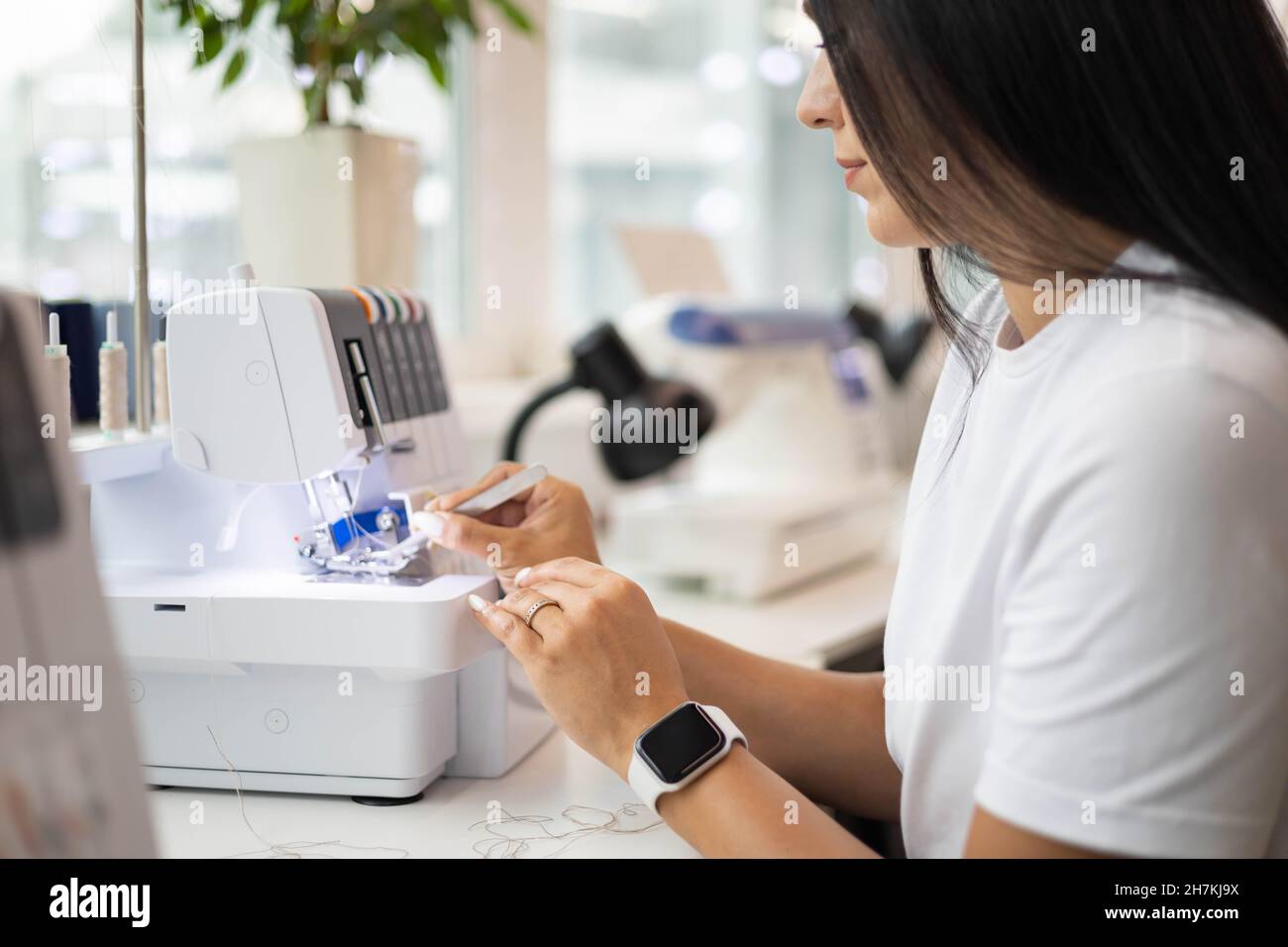 Professional female seamstress thread a needle use electric sewing ...