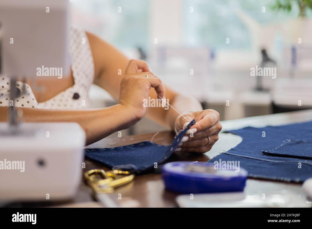 Closeup hands of seamstress woman connecting tissue pattern use thread ...