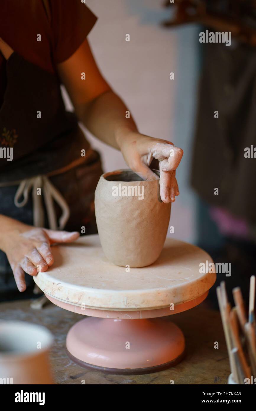Ceramist female concentrated shaping potter jug in studio. Woman visit ...