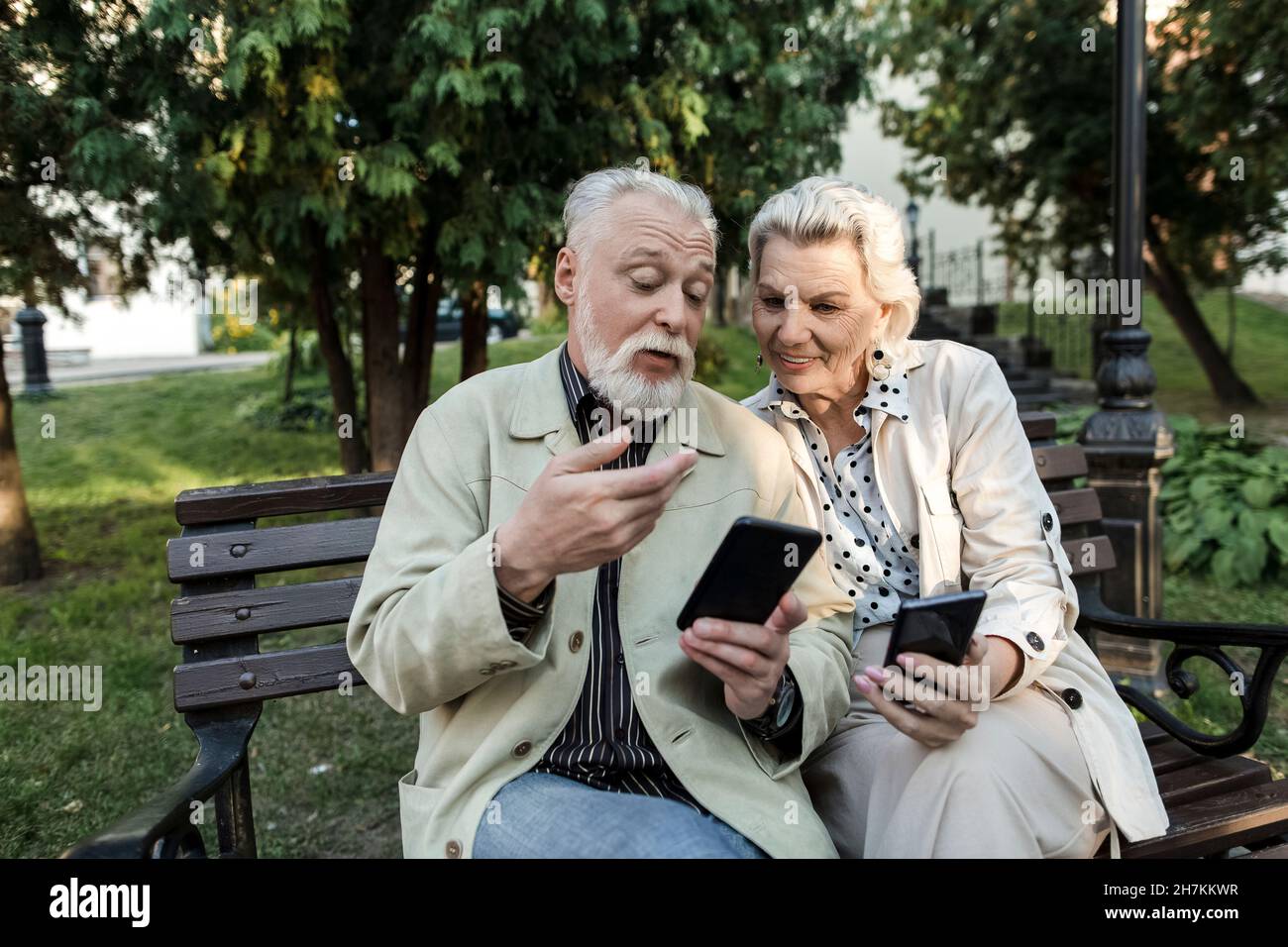 Couple using smart phones while sitting on bench Stock Photo - Alamy