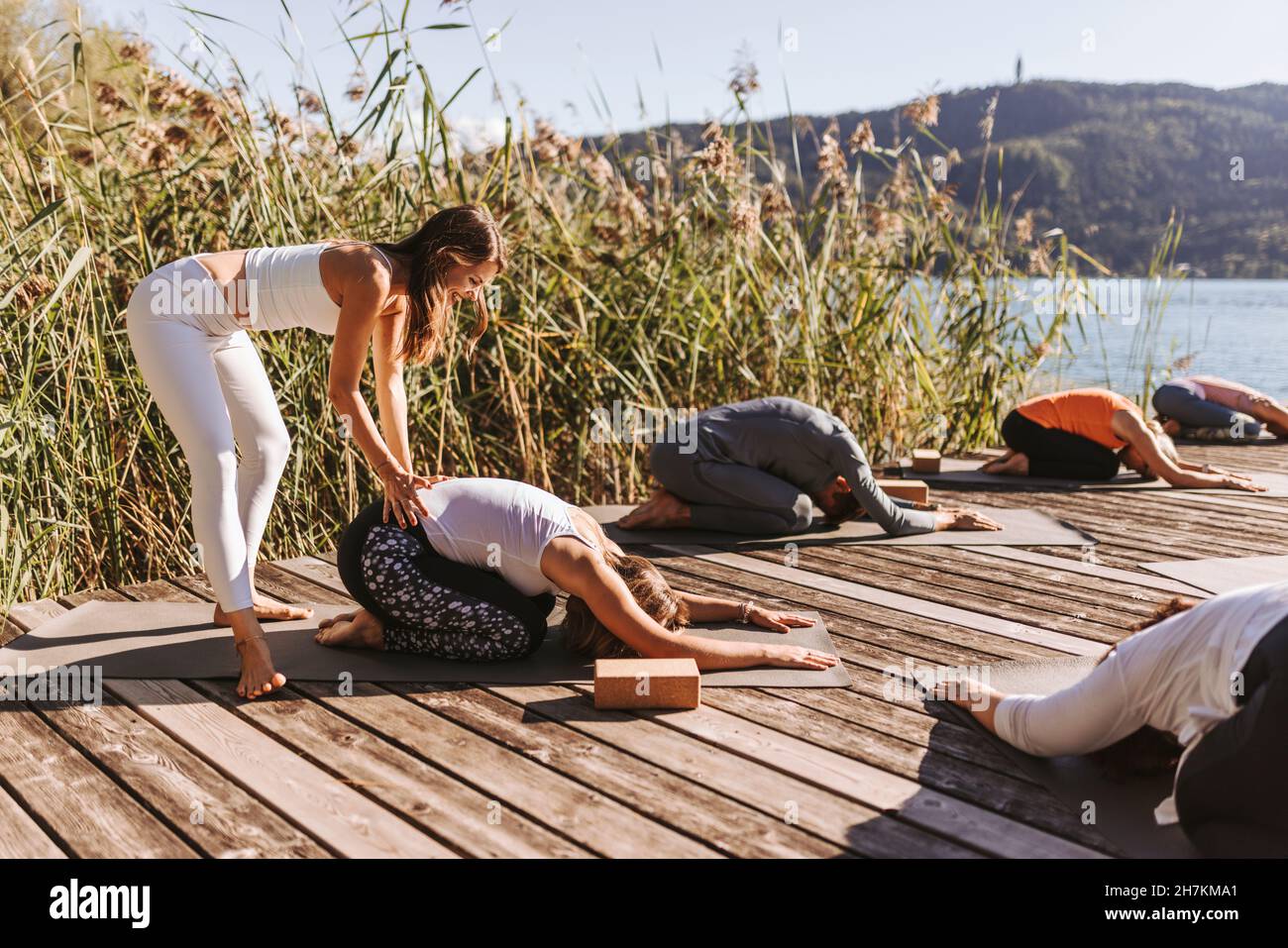 Female instructor assisting woman during yoga class Stock Photo - Alamy