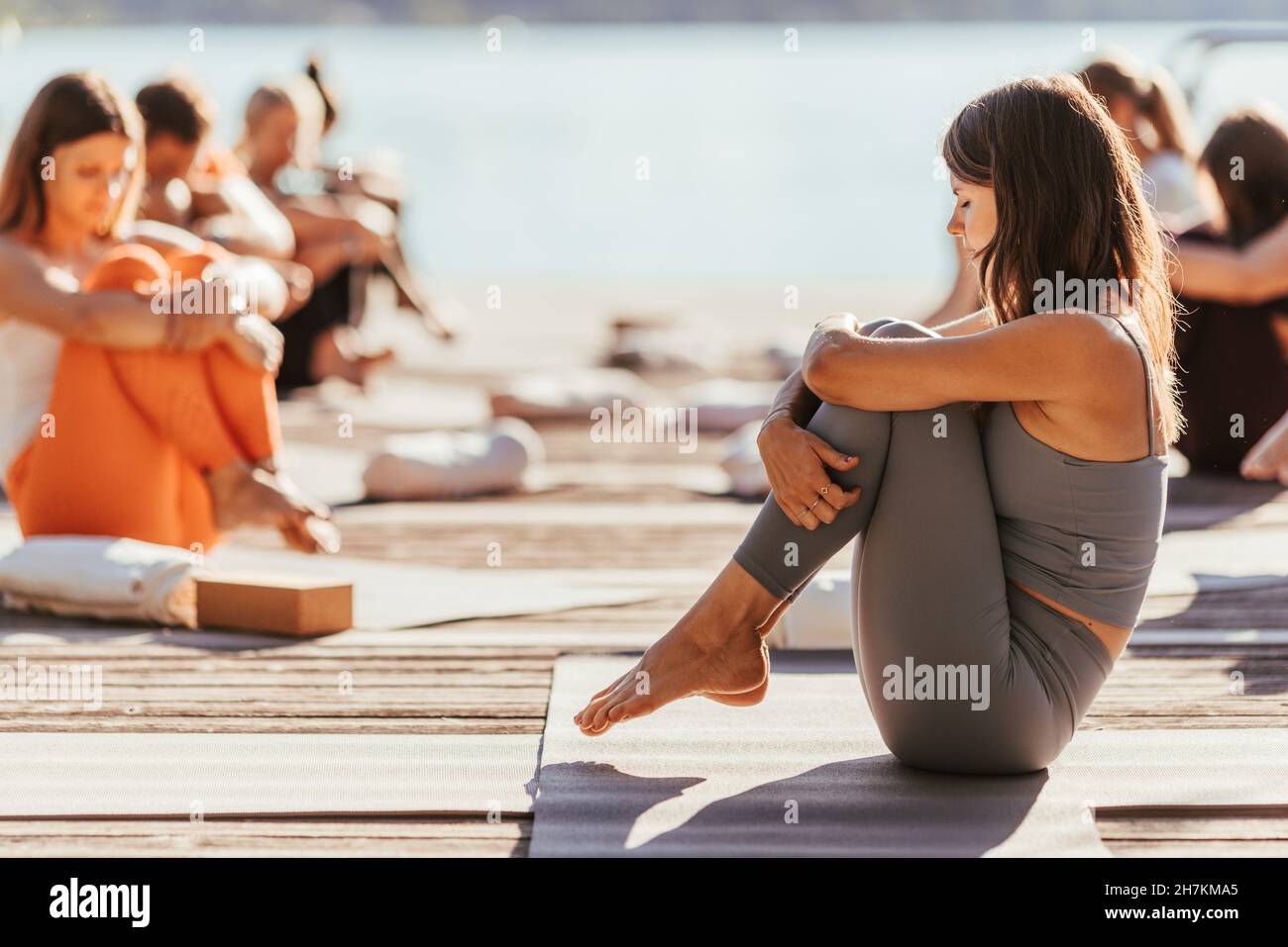 Female instructor hugging knees during yoga class Stock Photo - Alamy