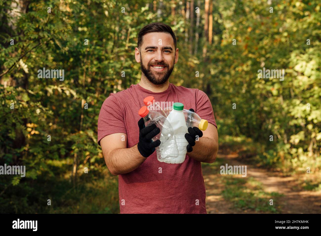 Male activist holding plastic bottles in forest Stock Photo - Alamy