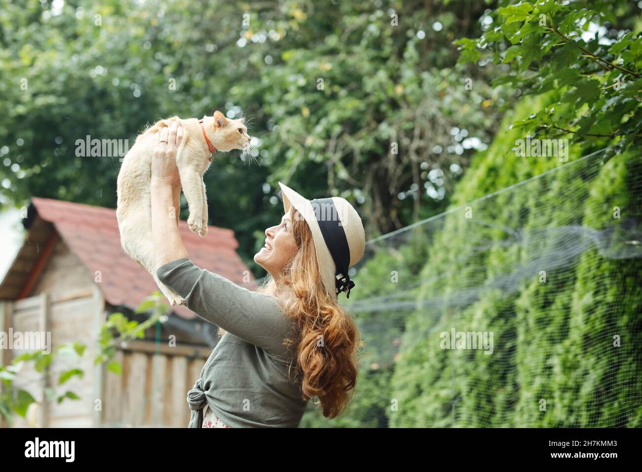 Smiling mature woman lifting cat in backyard Stock Photo - Alamy
