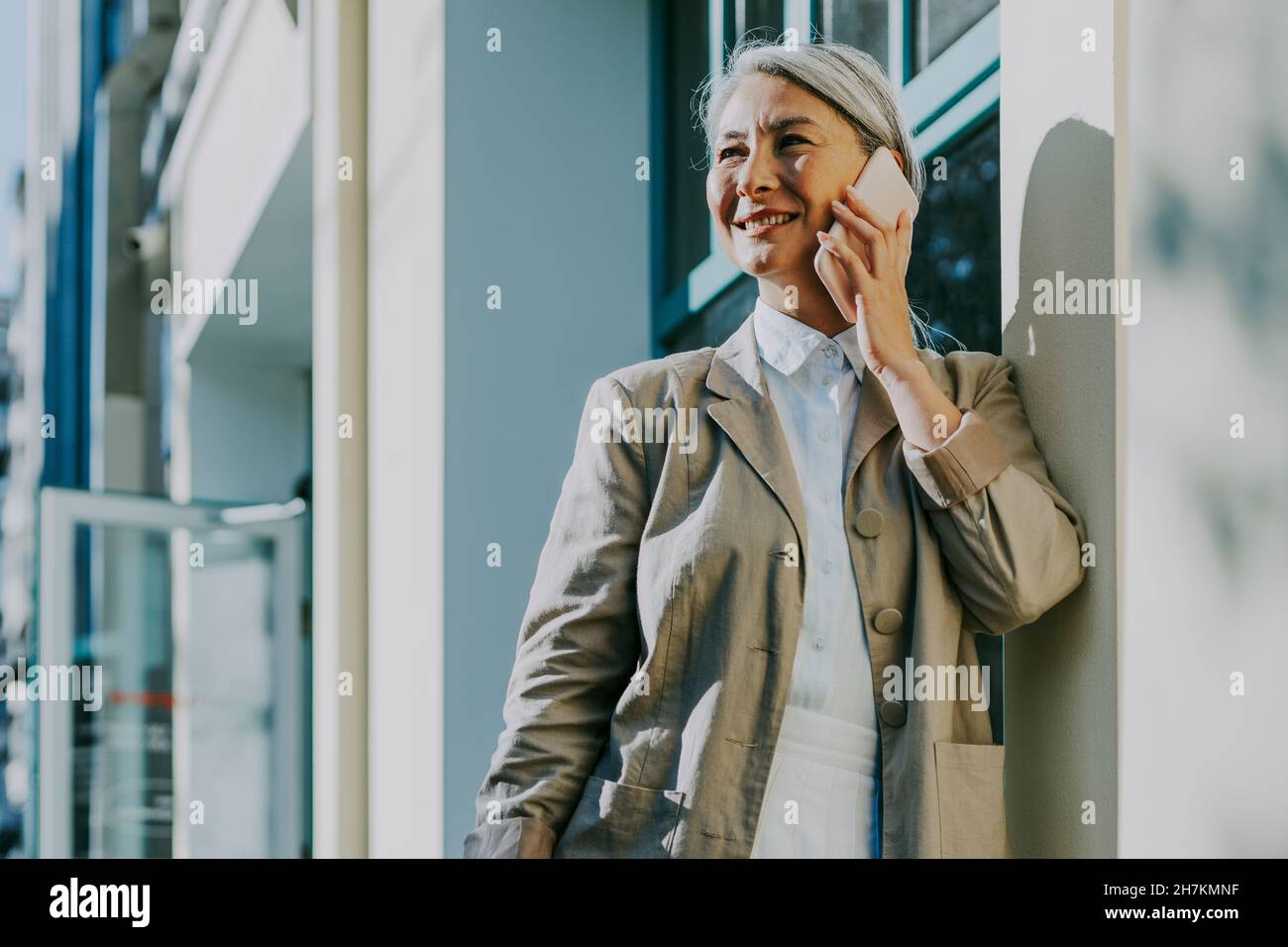 Woman smiling while talking on smart phone outside coffee shop Stock ...