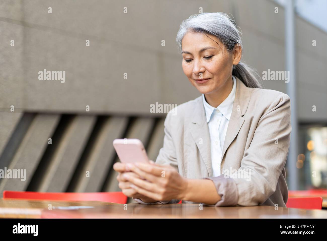 Mature woman text messaging through smart phone at sidewalk cafe Stock ...