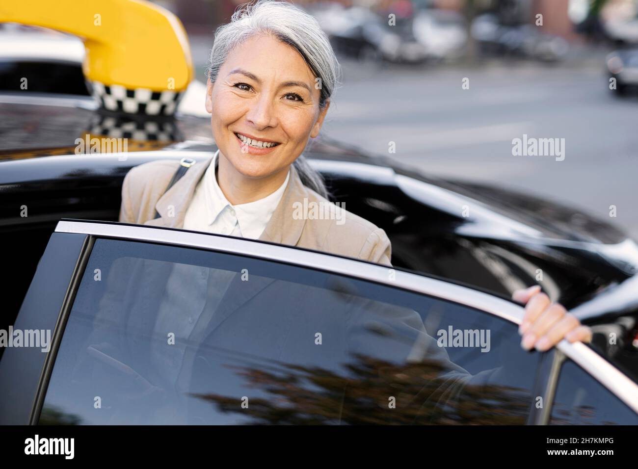 Smiling woman wit gray hair entering in taxi Stock Photo - Alamy