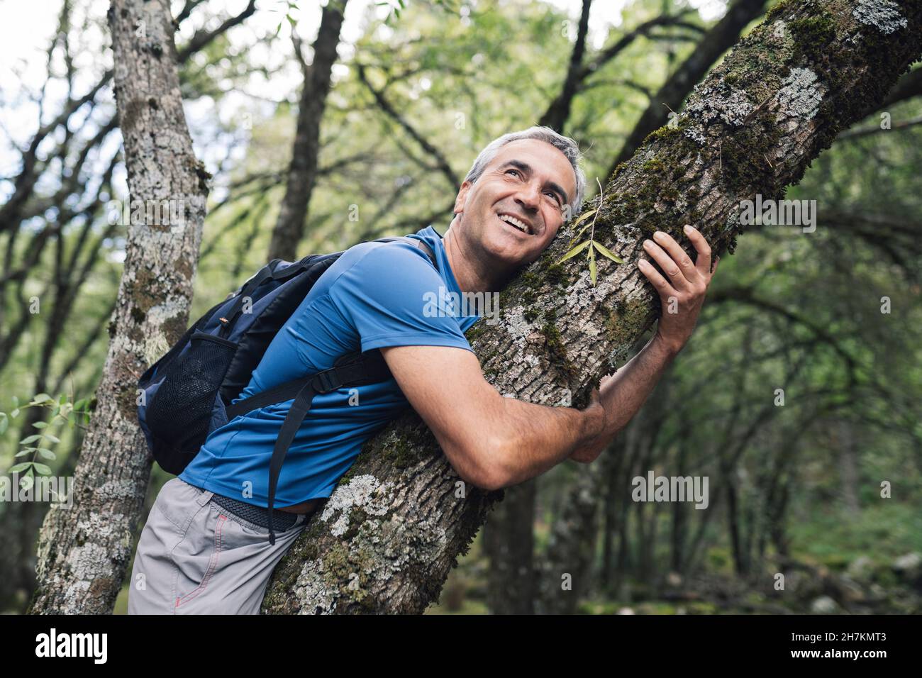 Mature man hugging tree in forest Stock Photo - Alamy