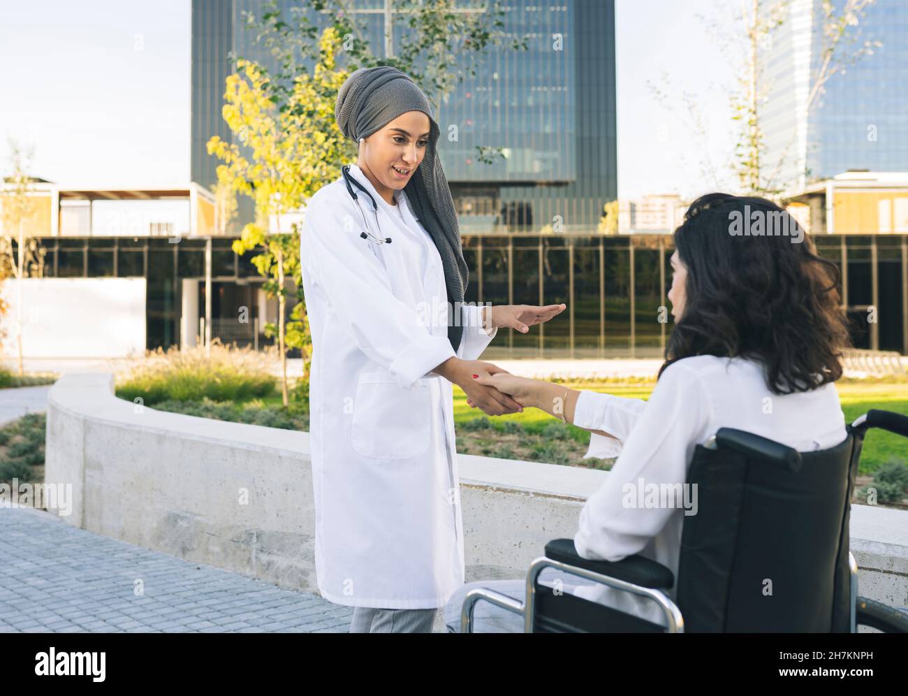Smiling female healthcare worker walking toward patient sitting on ...