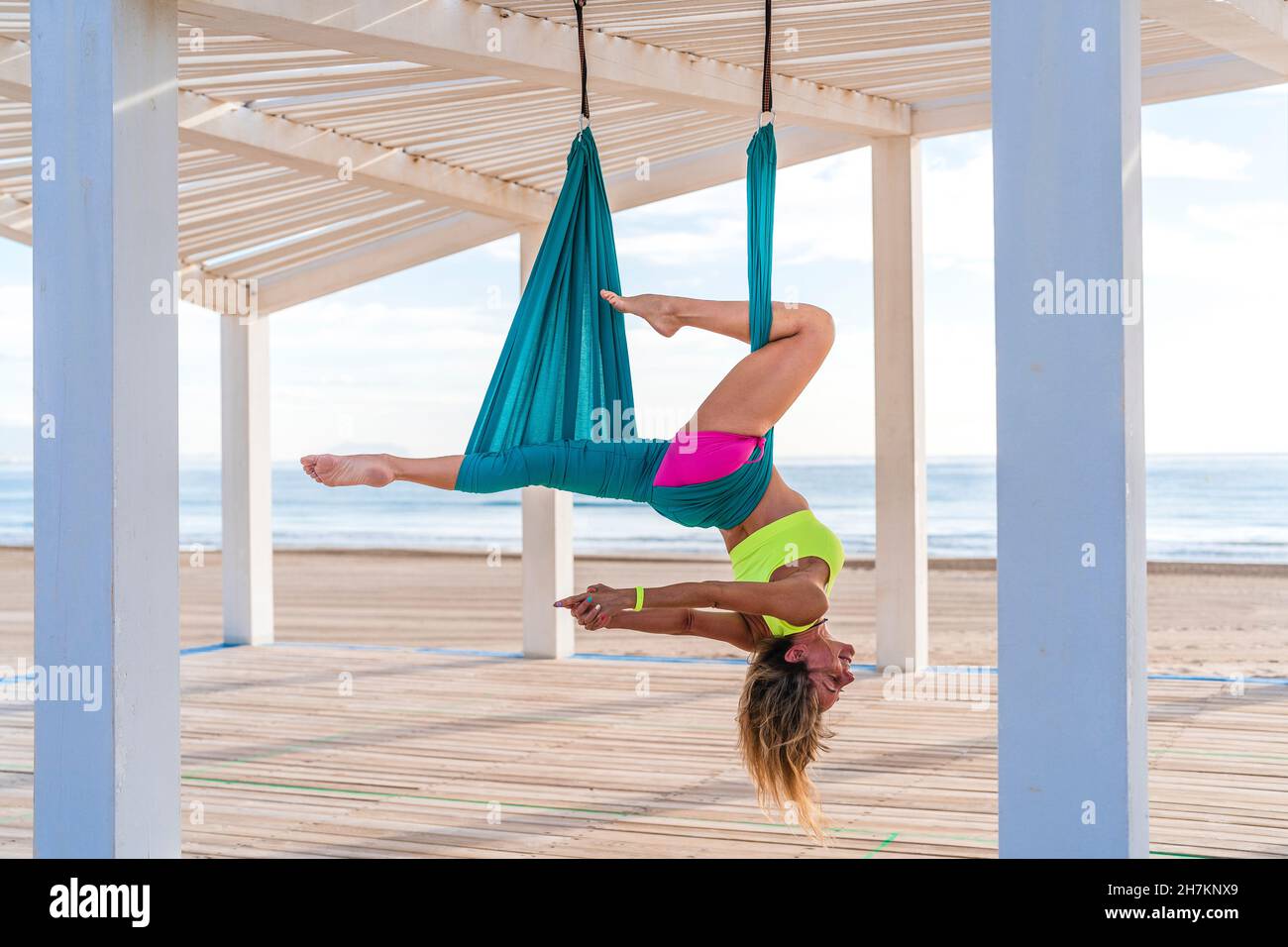 Flexible female acrobat exercising under shade at beach Stock Photo - Alamy
