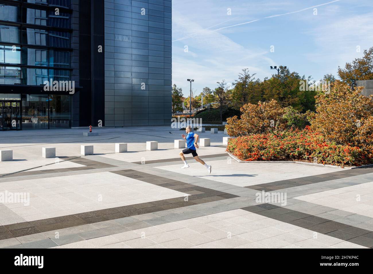 Young male athlete running on footpath in front of building Stock Photo ...