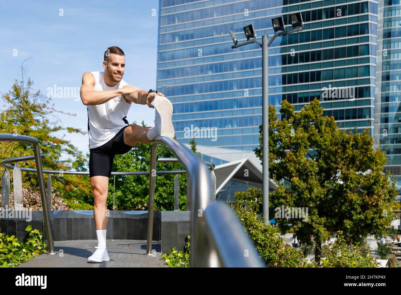 Young sportsman stretching leg on railing Stock Photo - Alamy