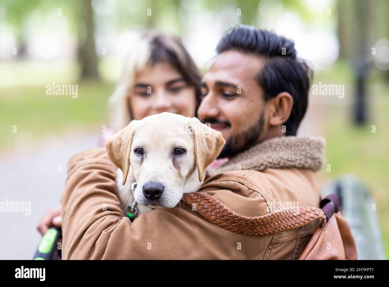 Smiling young man carrying dog in public park Stock Photo - Alamy