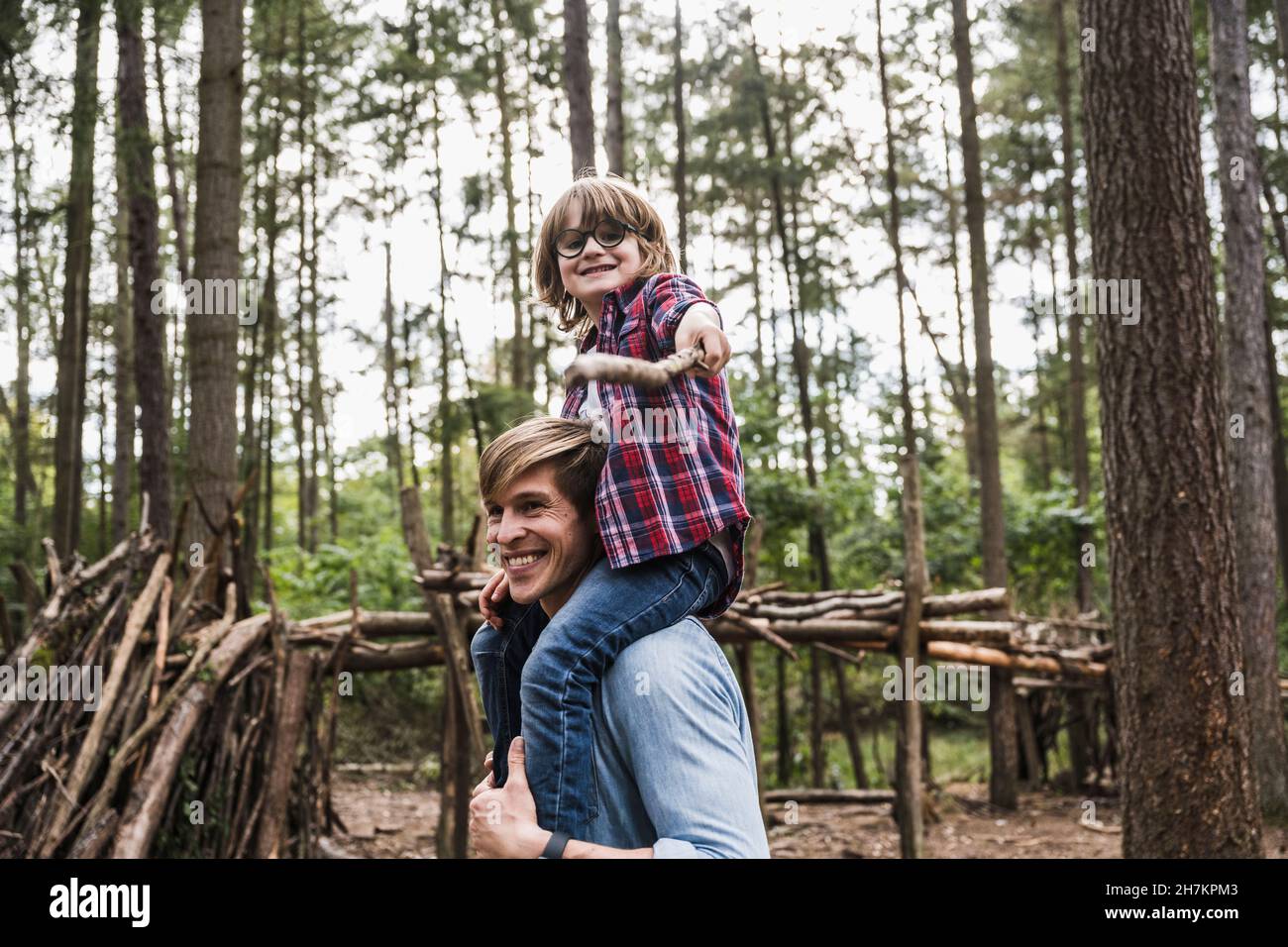 Smiling man carrying boy on shoulders at forest Stock Photo - Alamy