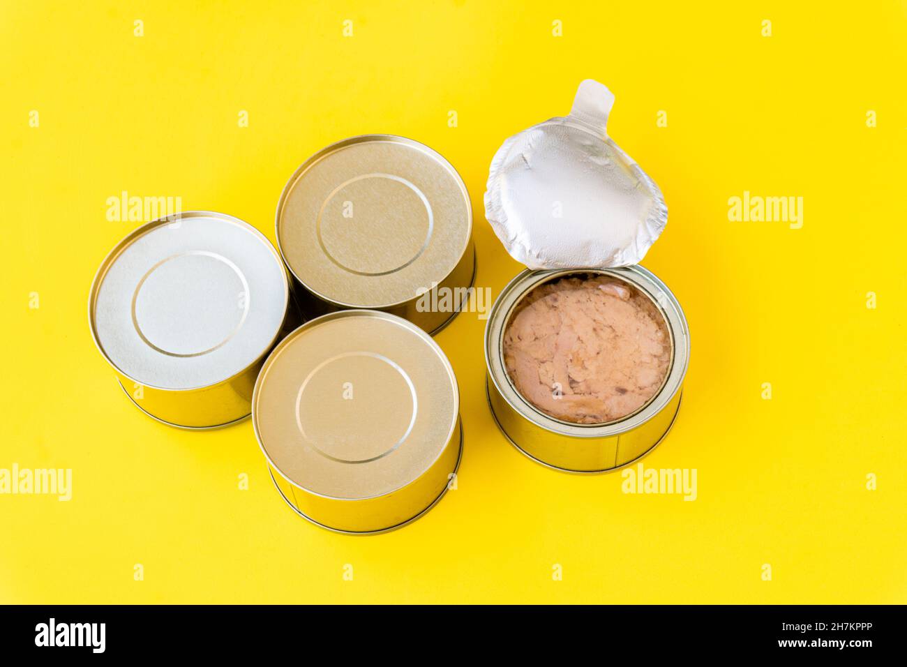 Open and three closed tuna cans on a yellow background Stock Photo - Alamy