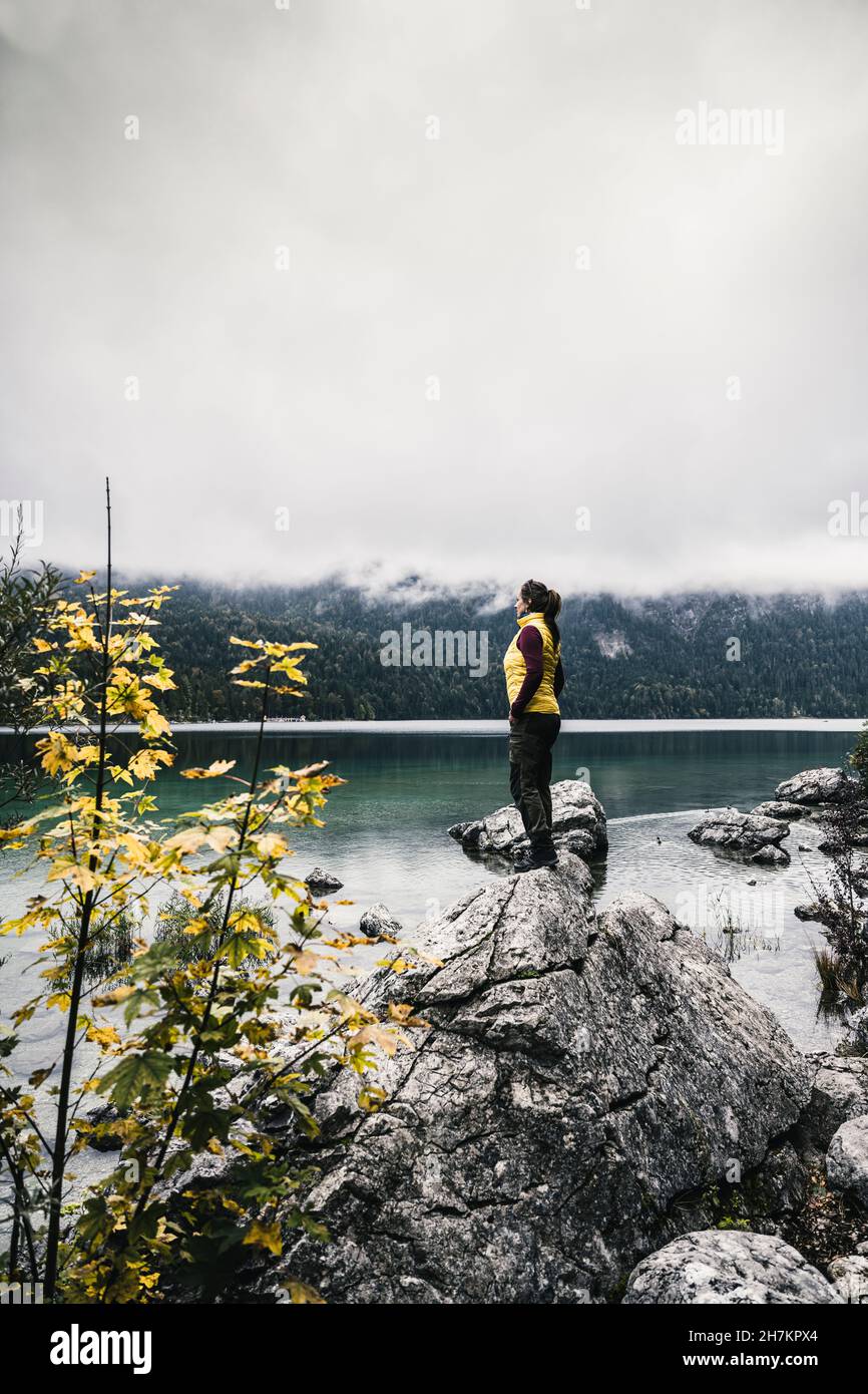 Woman standing on rock by lake Stock Photo - Alamy