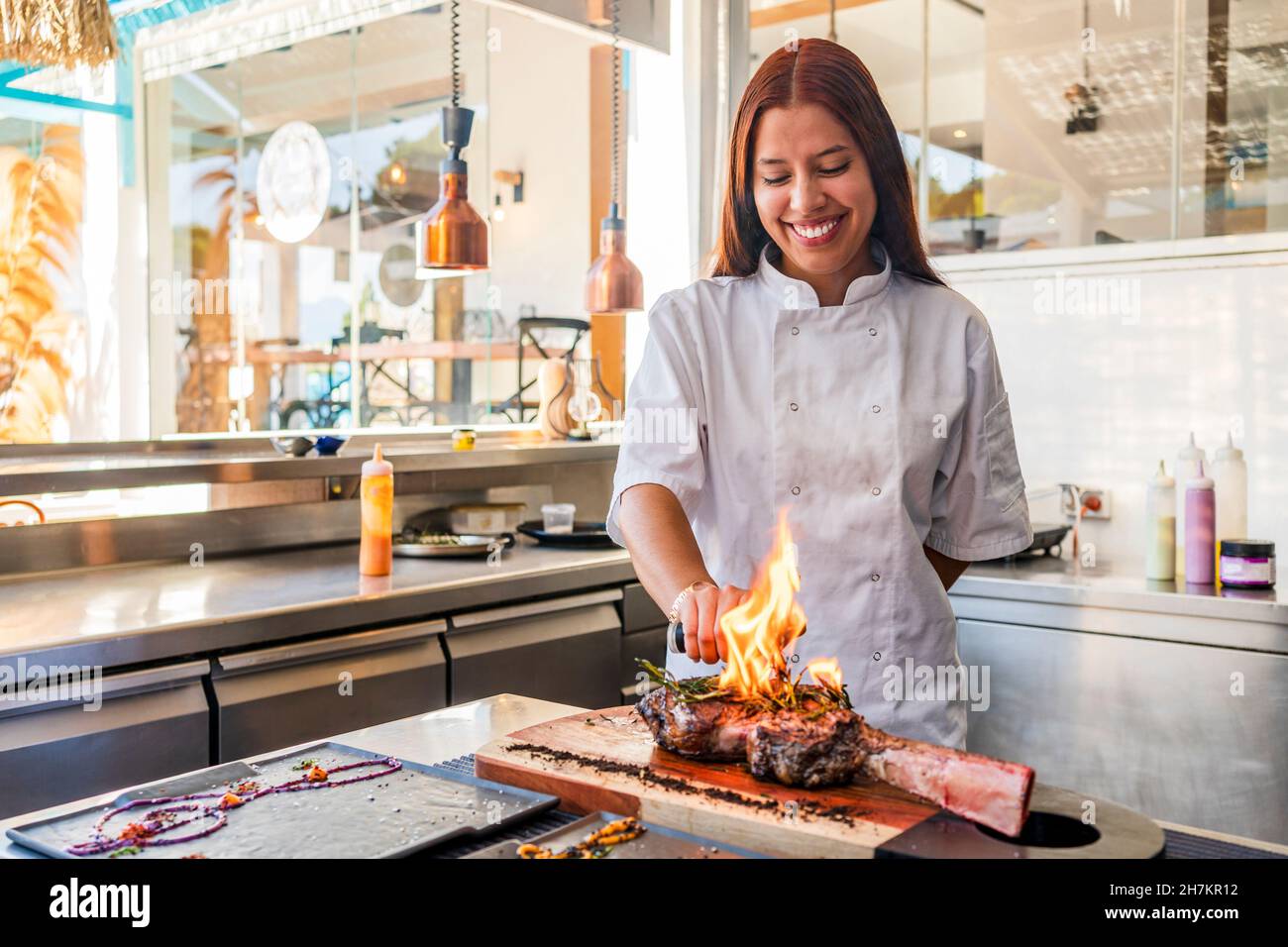 Smiling female chef smoking steak in kitchen Stock Photo - Alamy