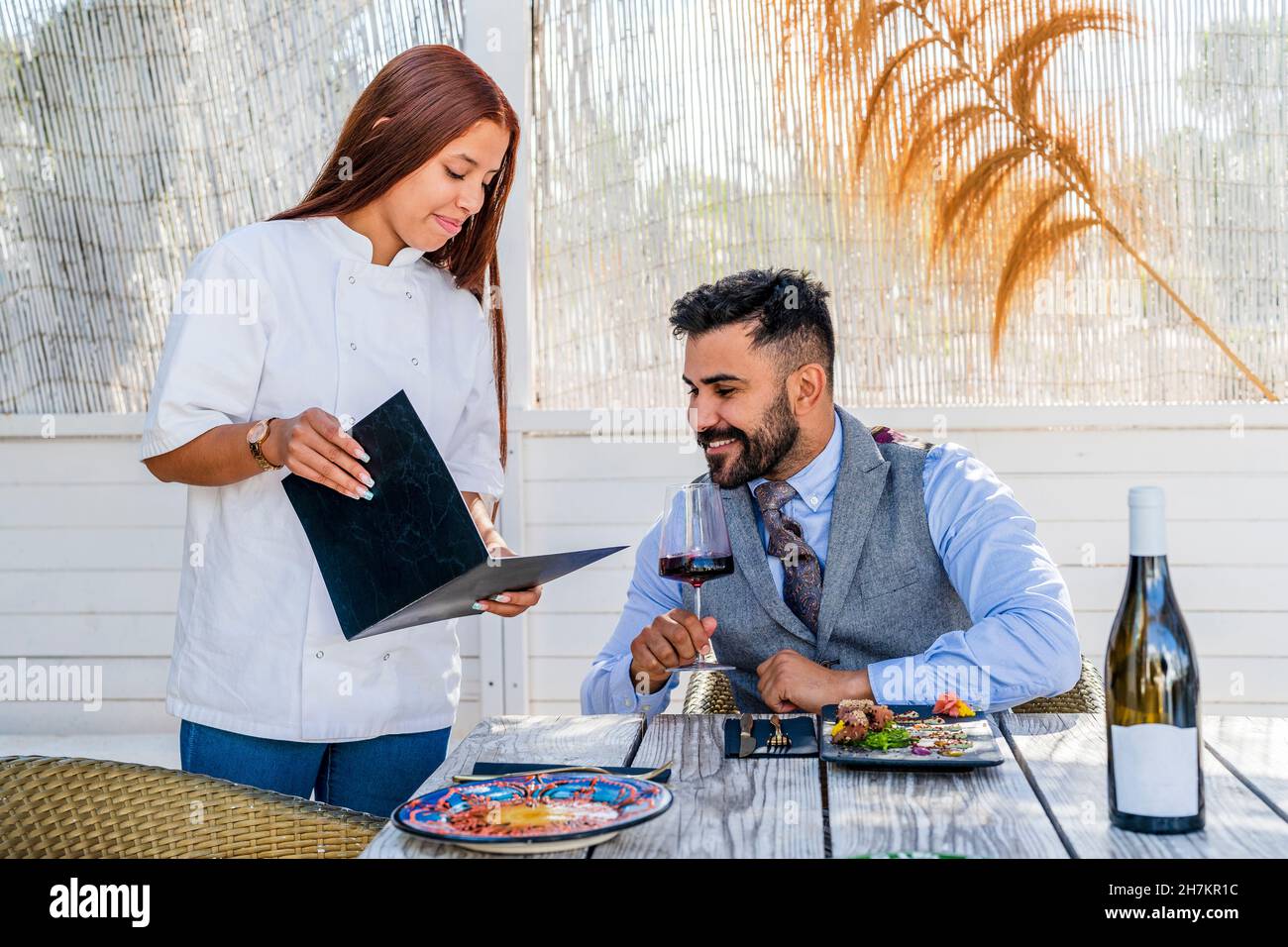 Waitress showing menu to male customer at restaurant Stock Photo - Alamy