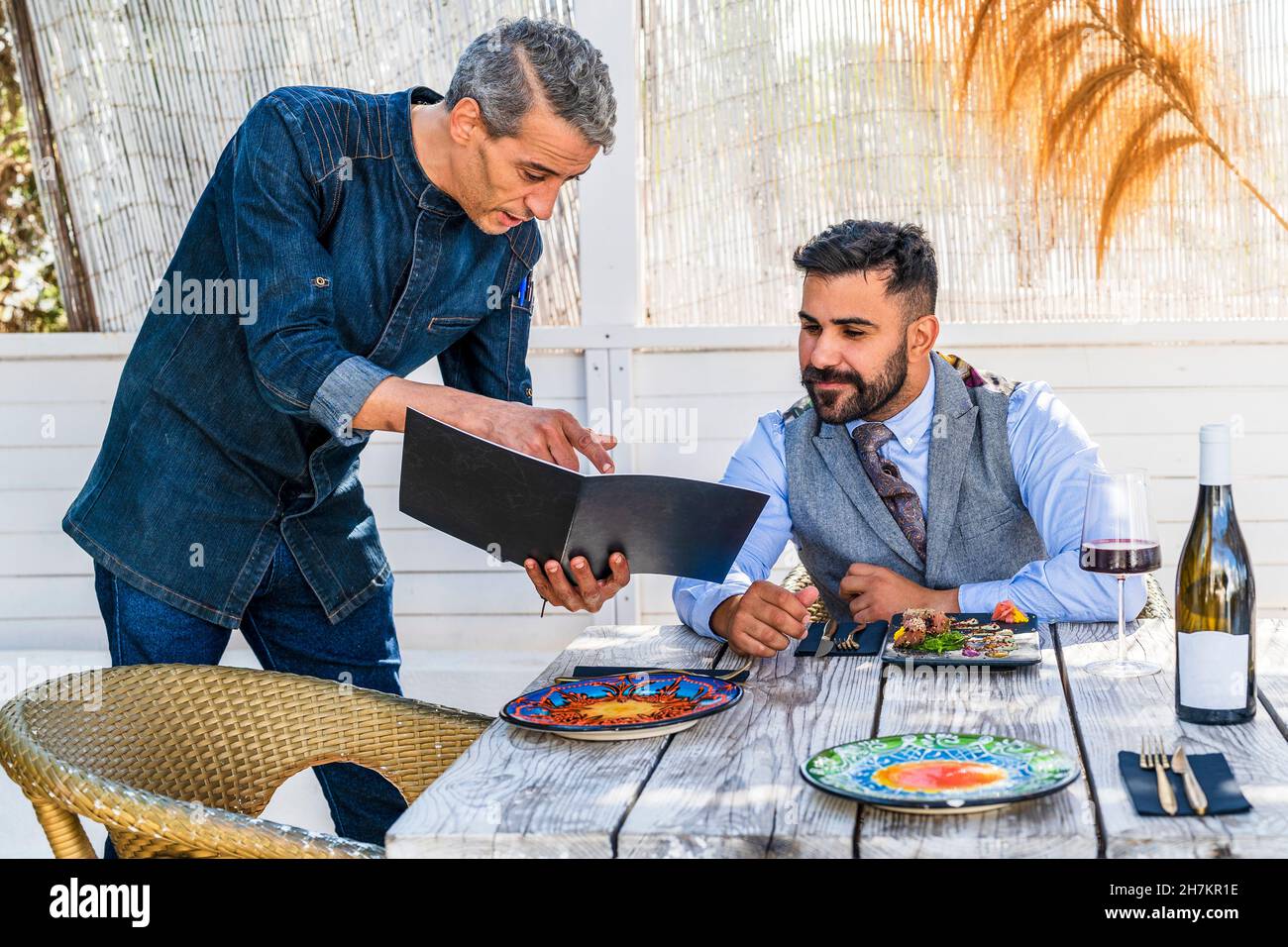 Male chef showing menu to customer at restaurant Stock Photo - Alamy