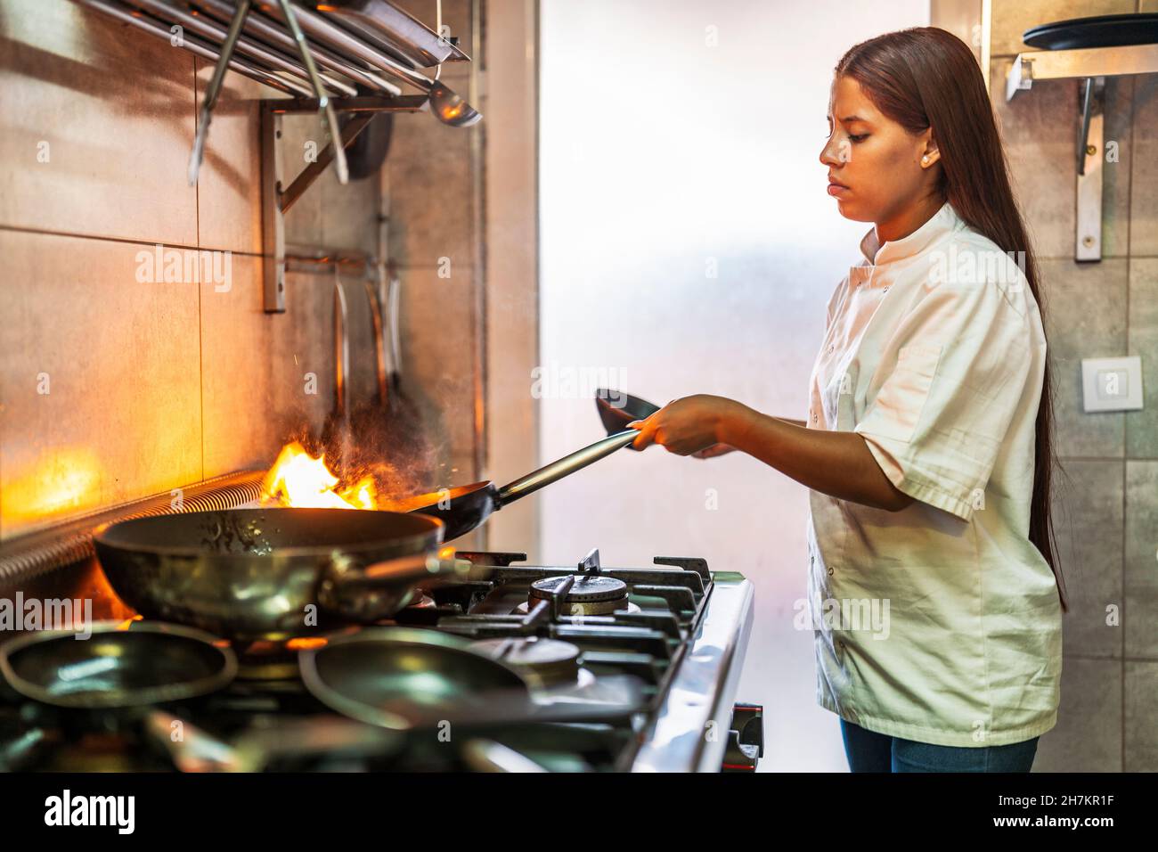 Female chef with pan cooking in kitchen Stock Photo - Alamy