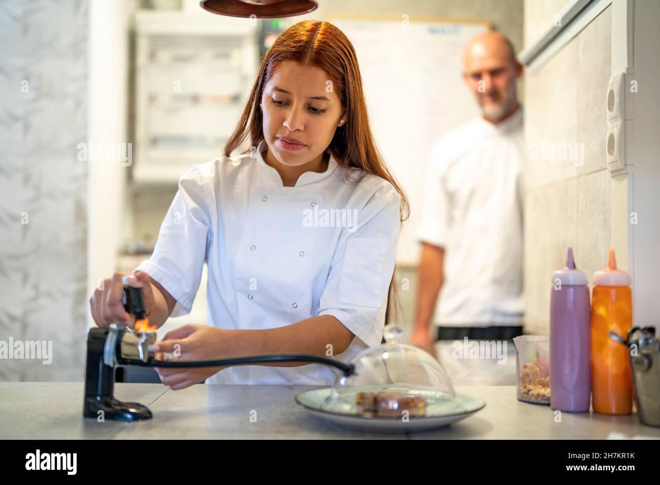 Female chef using smoke infuser while cooking in kitchen Stock Photo ...