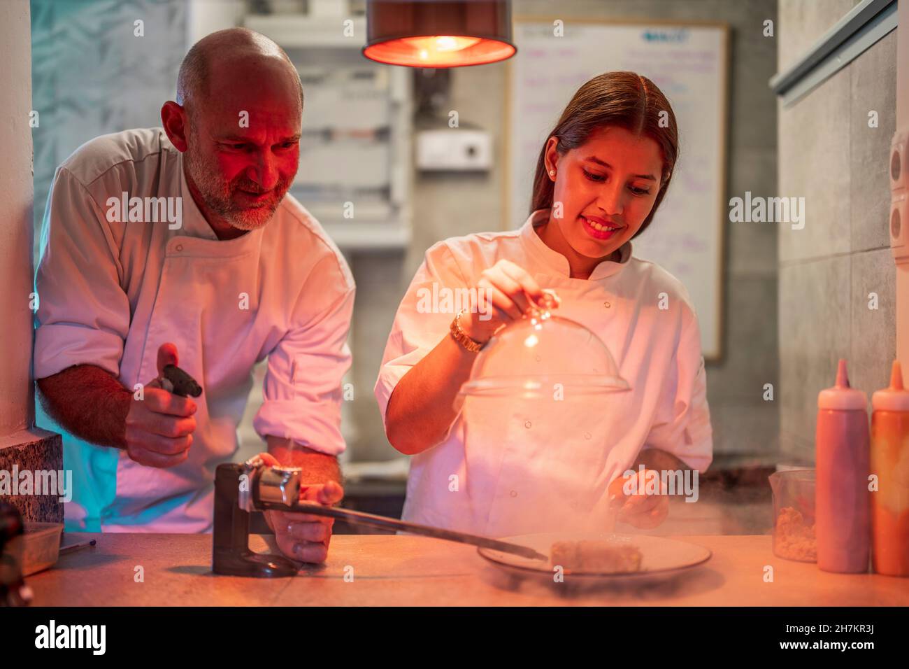 Male and female chefs smoking food in kitchen Stock Photo - Alamy
