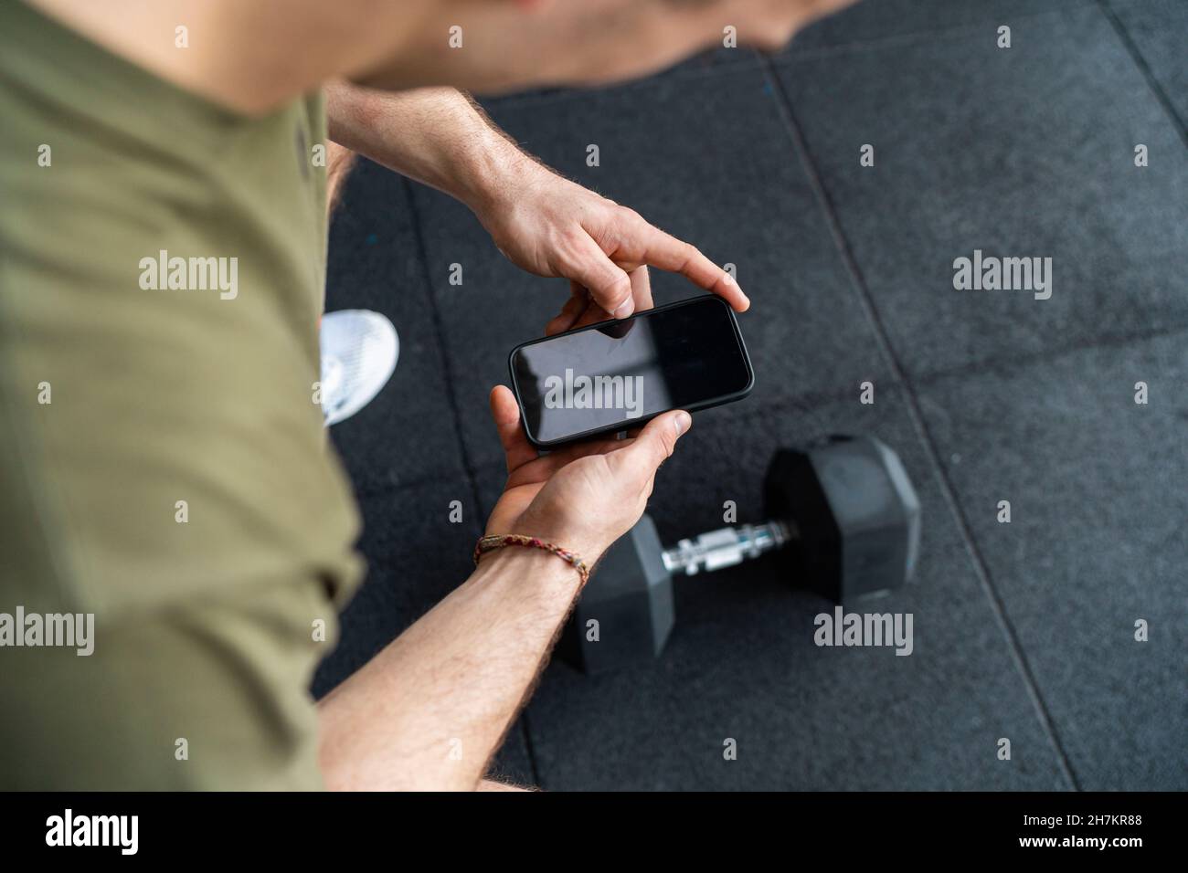 Young sportsman photographing dumbbell through smart phone in gym Stock ...