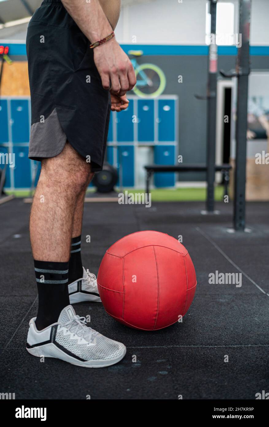 Male athlete standing by red sports ball in health club Stock Photo - Alamy