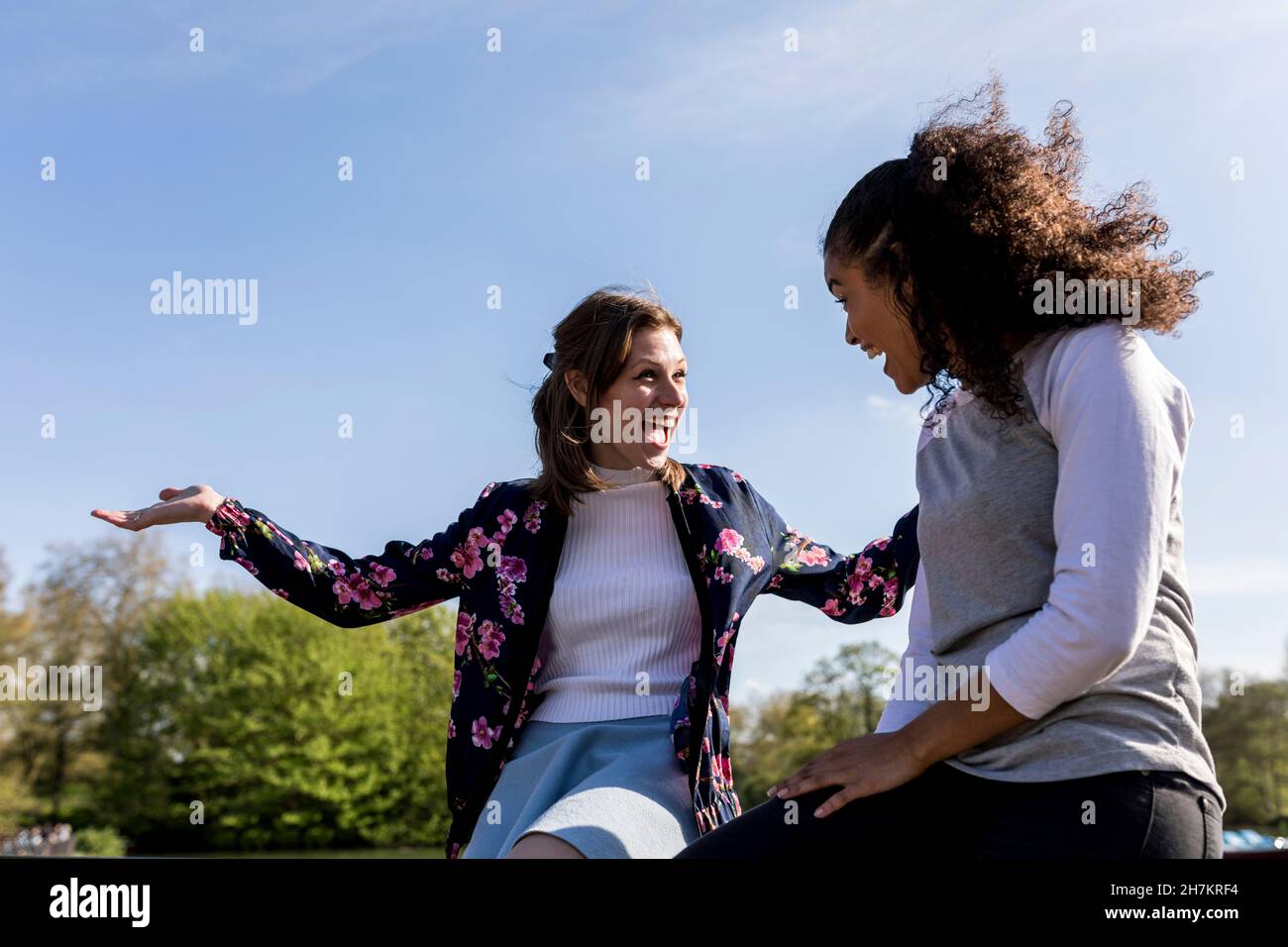 Happy friends talking in public park Stock Photo - Alamy