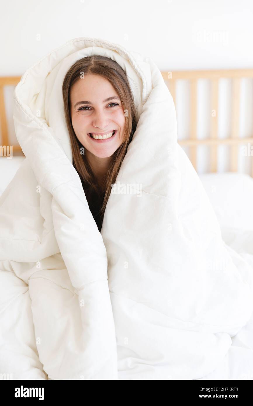 Smiling girl wrapped in white blanket at home Stock Photo - Alamy