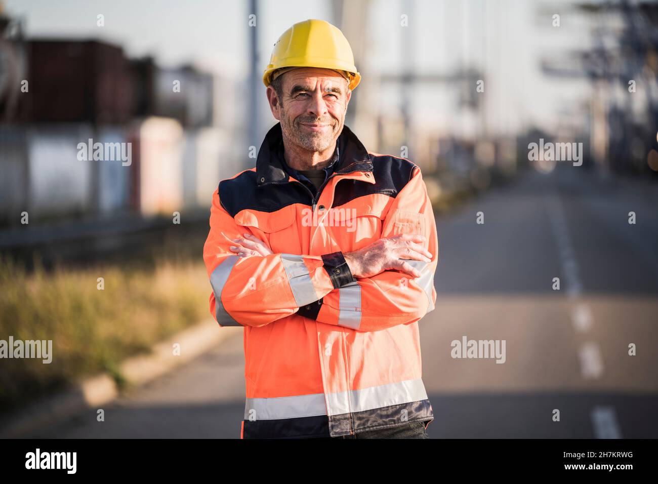 Smiling male dock worker with arms crossed on street at industry Stock ...