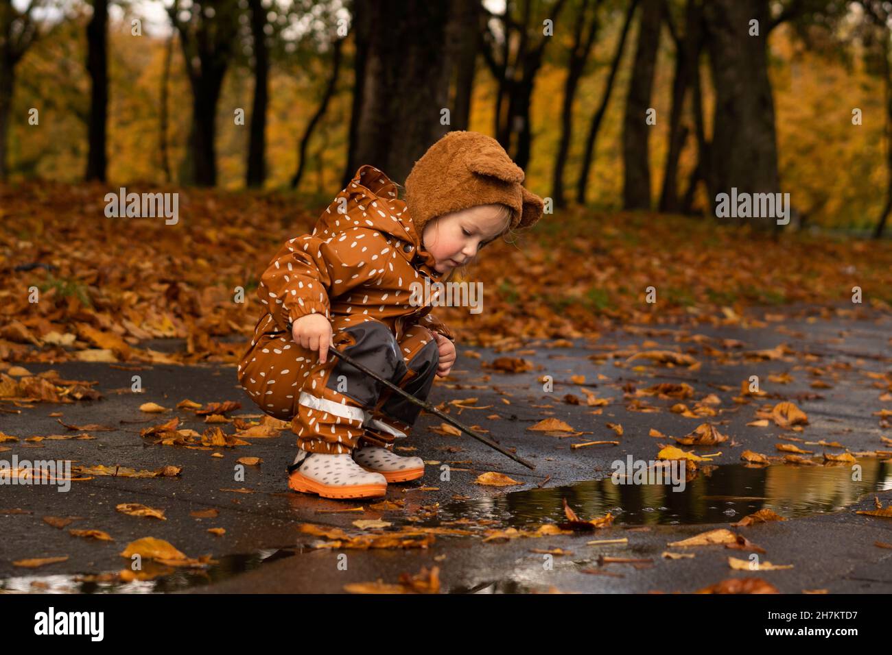 Toddler with stick playing at puddle Stock Photo - Alamy