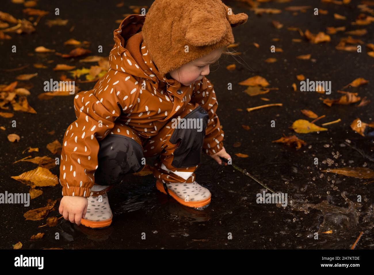 Girl playing in puddle on road Stock Photo - Alamy