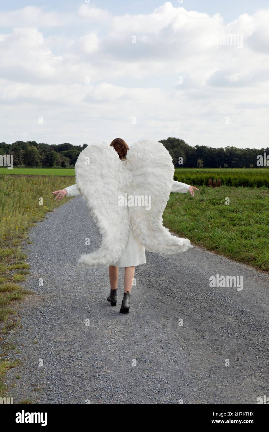 Carefree angel with arms outstretched walking on road Stock Photo - Alamy