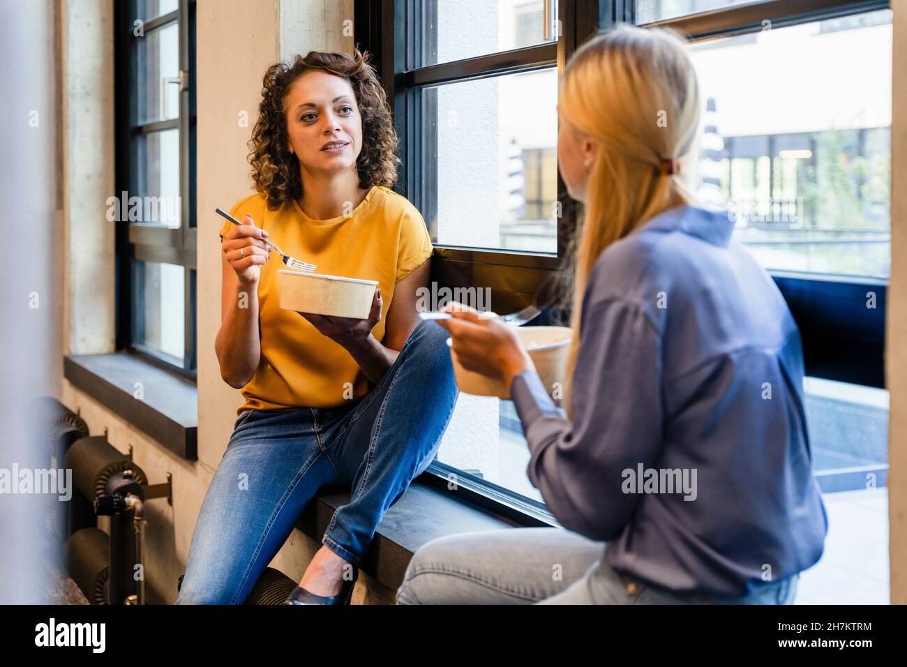 Businesswomen having lunch break at window sill Stock Photo - Alamy
