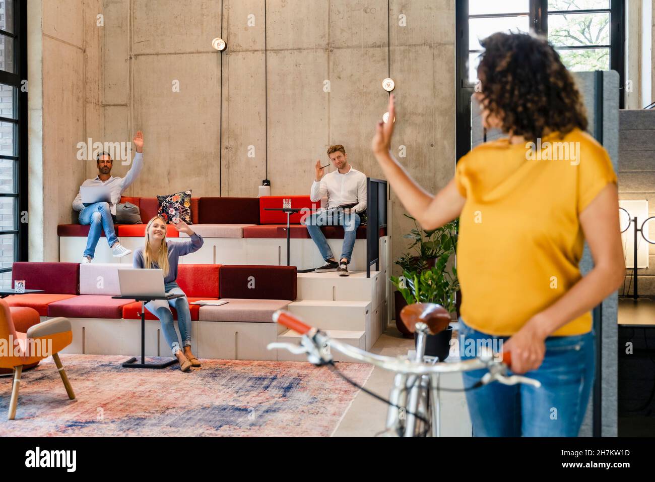 Coworkers waving hand to businesswoman in office Stock Photo - Alamy