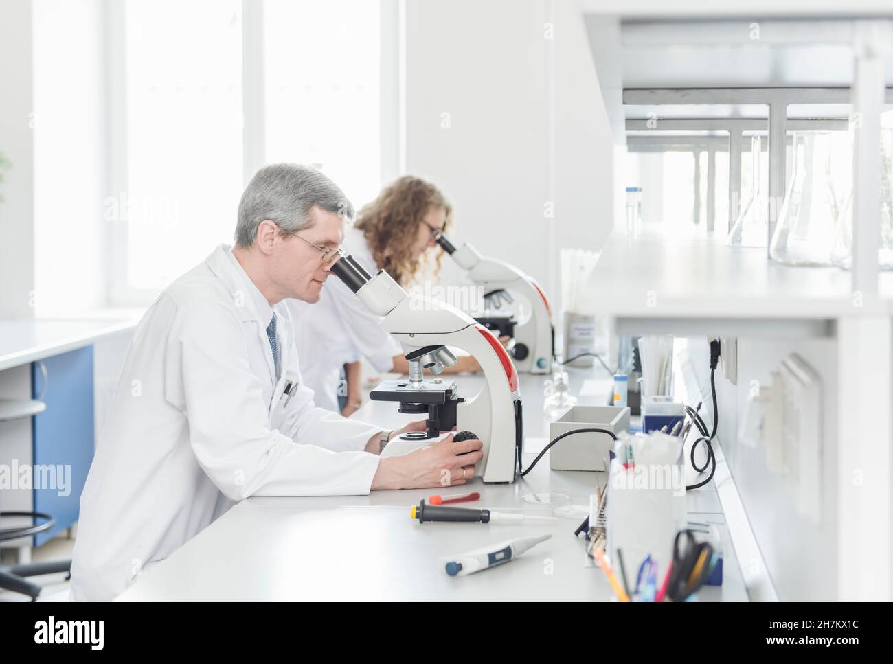 Scientists researching through microscope in laboratory Stock Photo - Alamy