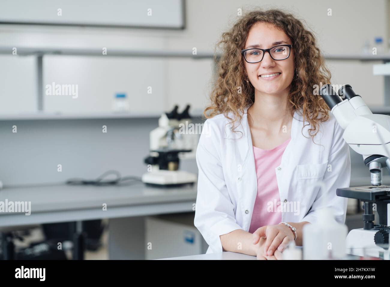 Smiling young scientist with microscope at laboratory desk Stock Photo ...