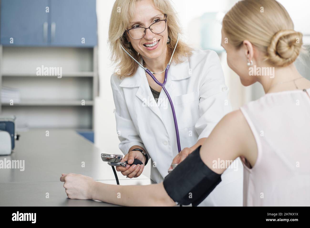 Smiling doctor checking patient with stethoscope in clinic Stock Photo ...